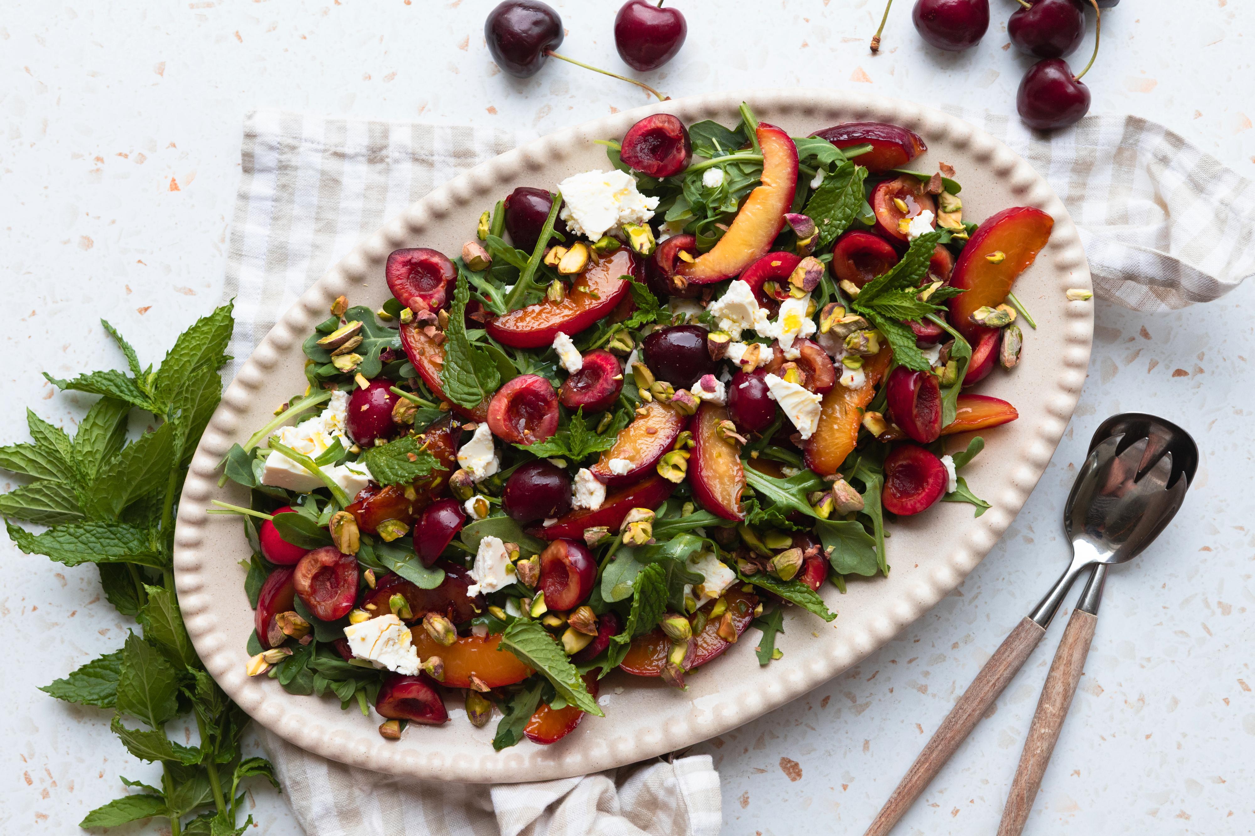 morell-og fetaostsalat med ruccola, mynte og grillet nektarin på avlangt, hvitt fat.